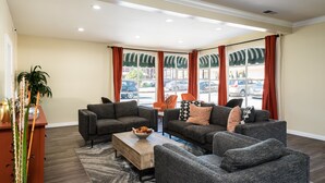 Uma sala de estar ampla com sofás cinza, uma mesa de centro de madeira e uma janela grande com cortinas.