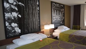 Quarto de hotel com duas camas, uma grande obra de arte floral na parede, televisão e janela com cortinas.