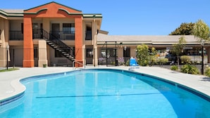 Um hotel com piscina, área coberta com assentos e escadaria que dá acesso aos andares superiores.