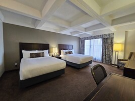 Quarto de hotel com duas camas, uma escrivaninha e uma cadeira.