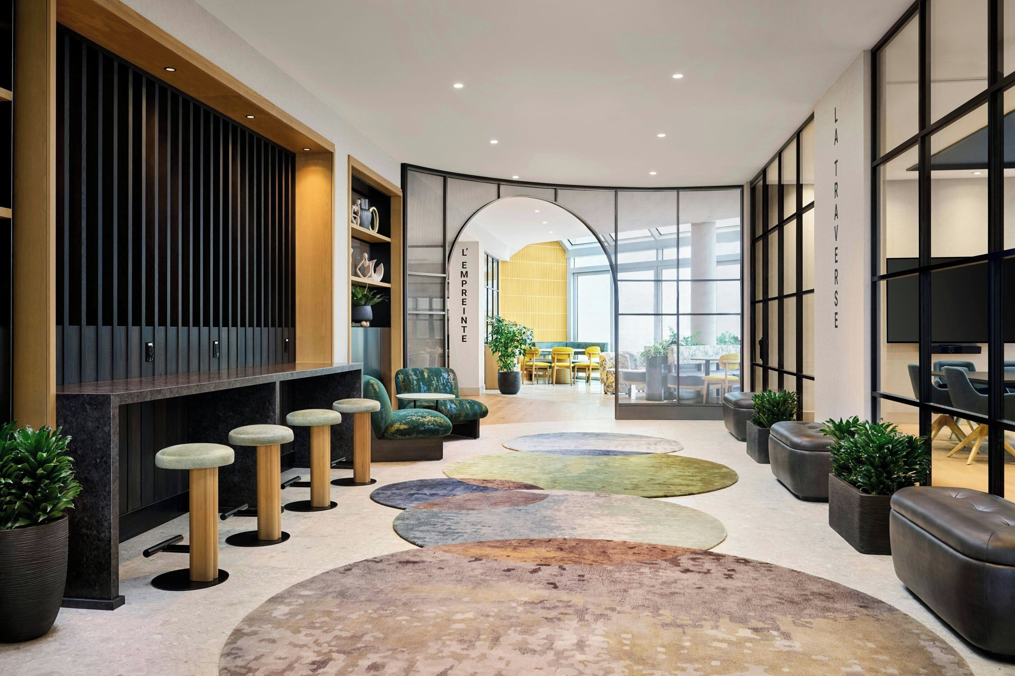Um interior moderno com uma área de estar em curva, um bar e uma vista através de um arco para uma área de refeições.