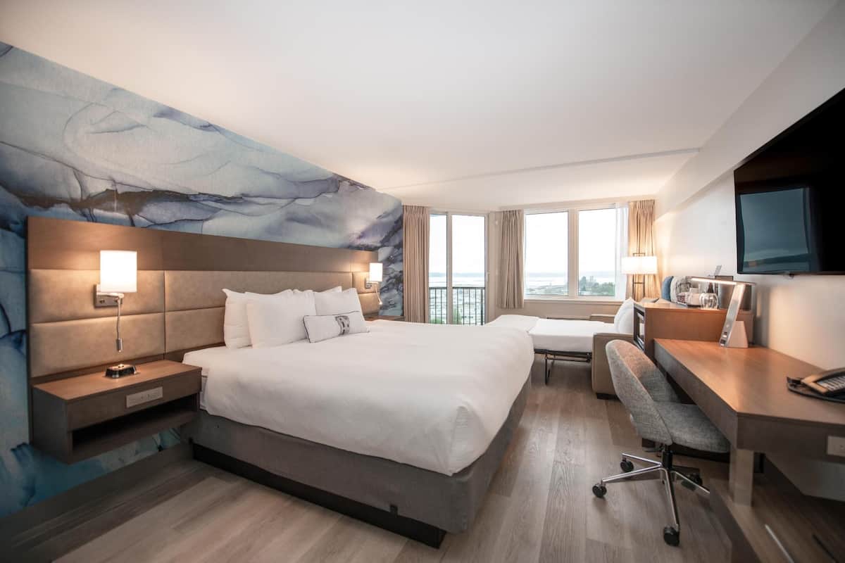 Quarto de hotel moderno com uma cama grande, uma escrivaninha e uma TV.