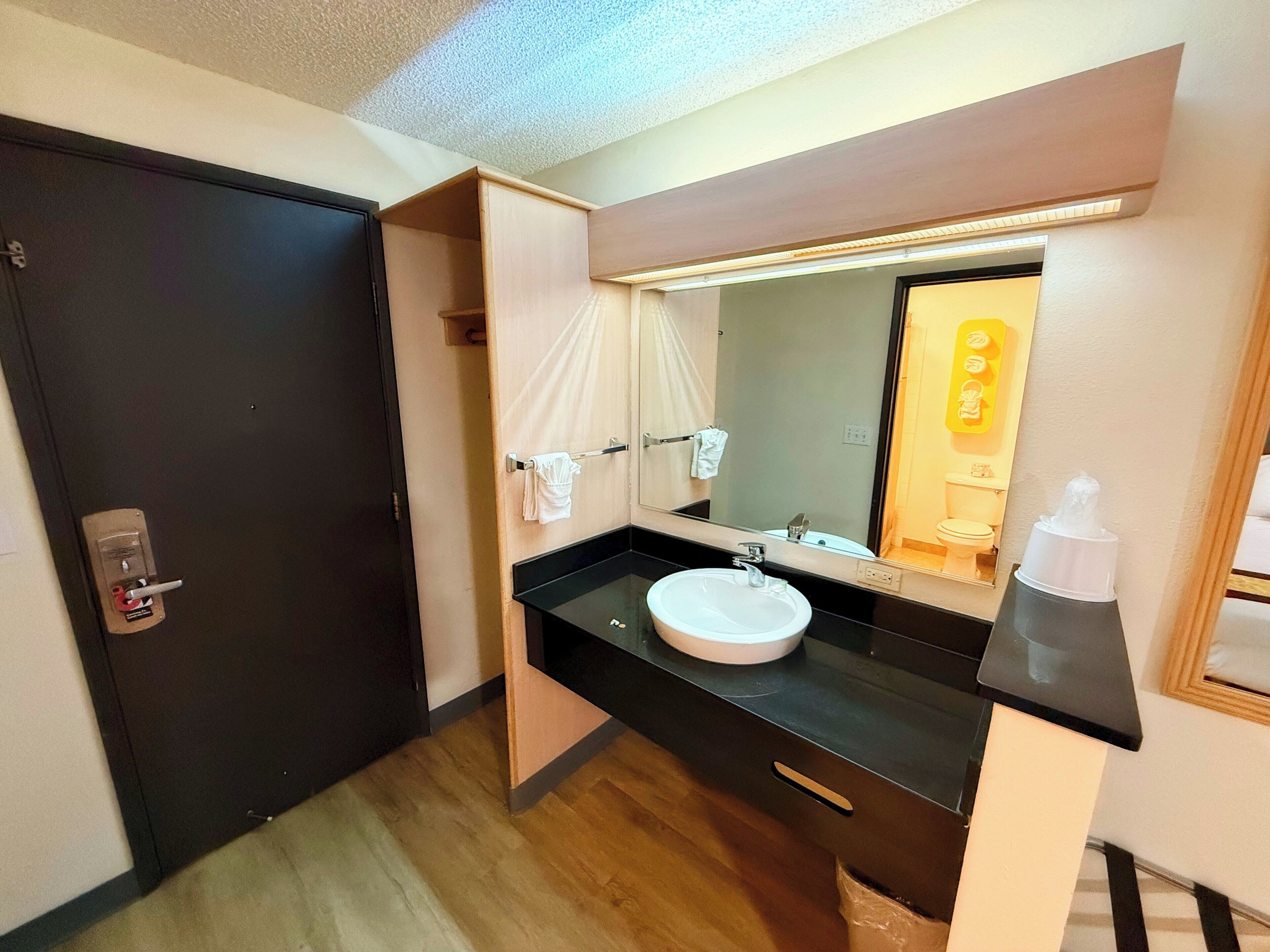 Casa de banho de hotel com lavatório, espelho, porta-toalhas e porta.