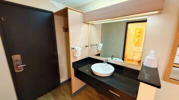 Casa de banho de hotel com lavatório, espelho, porta-toalhas e porta.