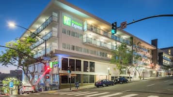 Edifício Holiday Inn Express com design moderno, situado numa esquina de rua com passadeira e semáforos.