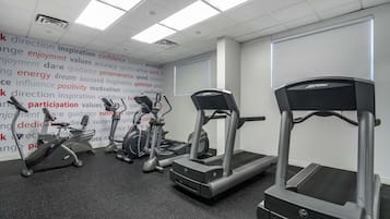 Uma academia com esteiras, elípticos e bicicletas ergométricas.