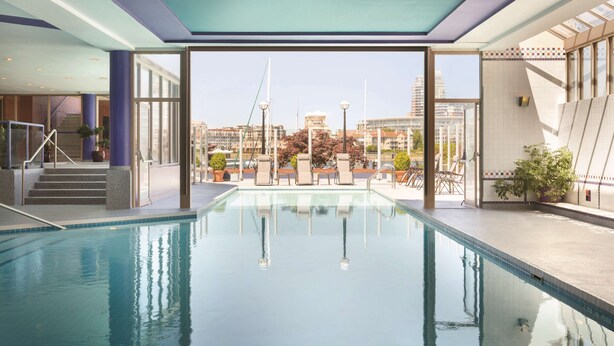 Piscina interna com vista clara para a paisagem urbana através de grandes janelas.
