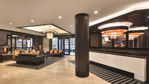 Um hall de hotel com balcão de recepção, área de estar e grandes janelas.