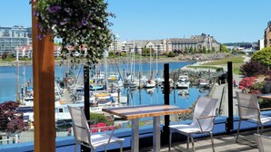 Terraço com mesa e cadeiras com vista para uma marina e barcos.
