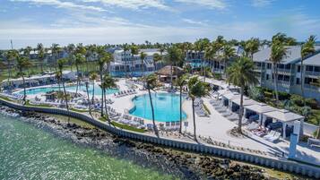 Resort com várias piscinas, áreas de estar e vista para a praia.