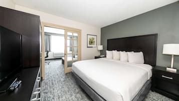 Quarto de hotel com uma cama grande, televisão, escrivaninha e porta para uma varanda.