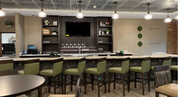 Uma área de bar moderna com televisão de tela plana, banquetas e balcão.