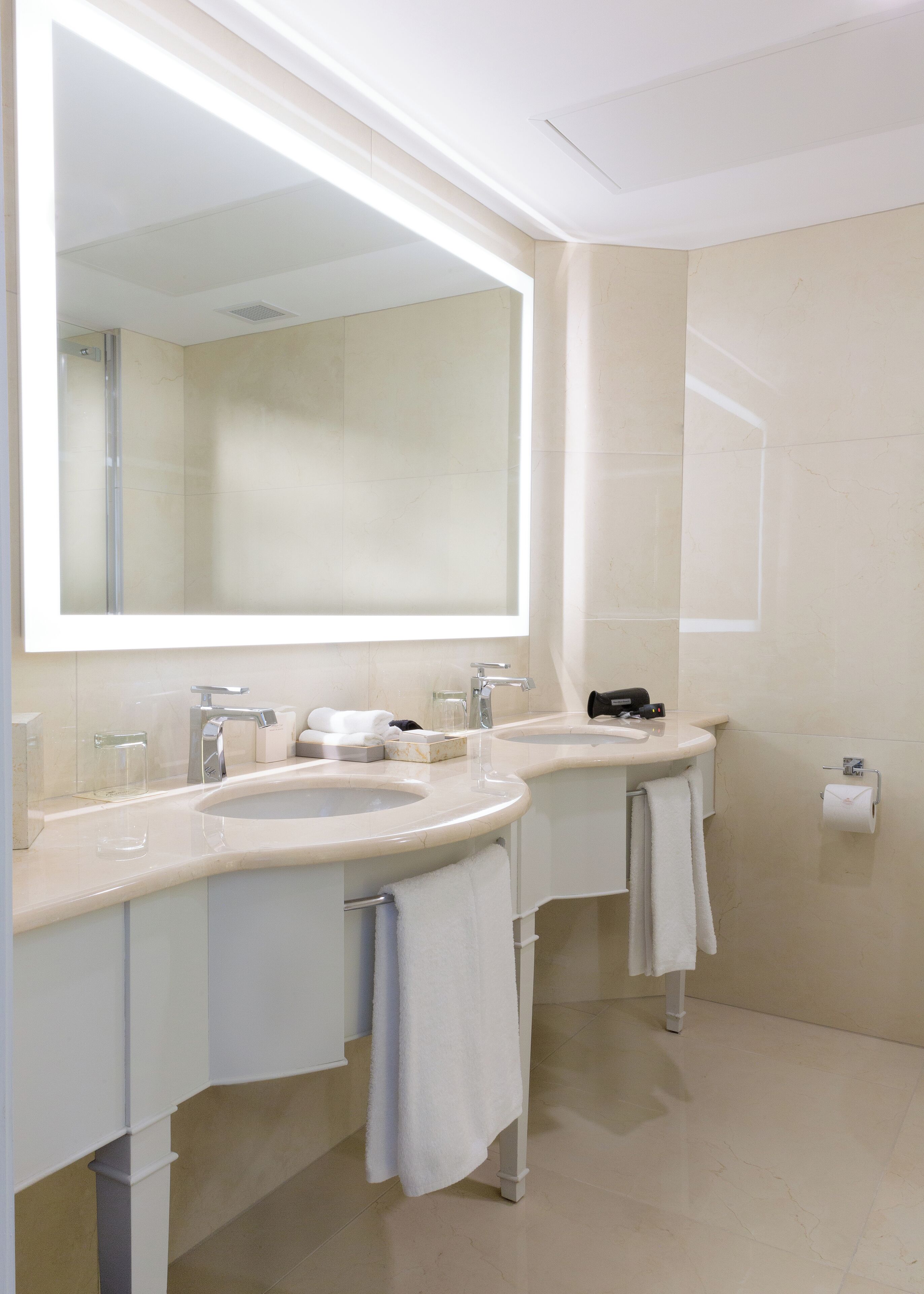 Casa de banho moderna com duas pias, um espelho grande e um porta-toalhas.