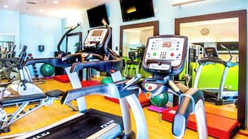 Uma academia com esteiras, bicicletas ergométricas e bolas de exercício.