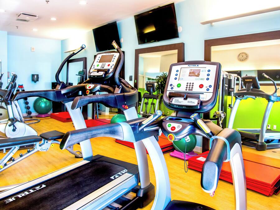 Uma academia com esteiras, bicicletas ergométricas e bolas de exercício.