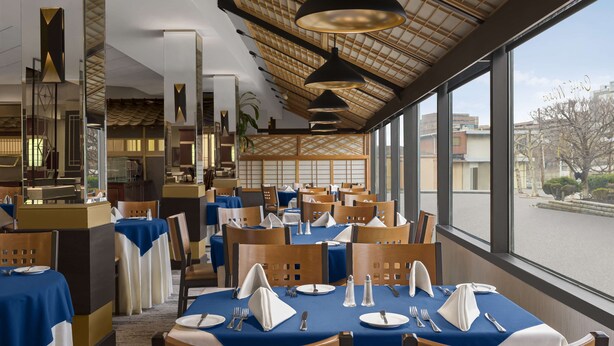 Um restaurante com mesas postas para refeições, grandes janelas e design de interiores moderno.