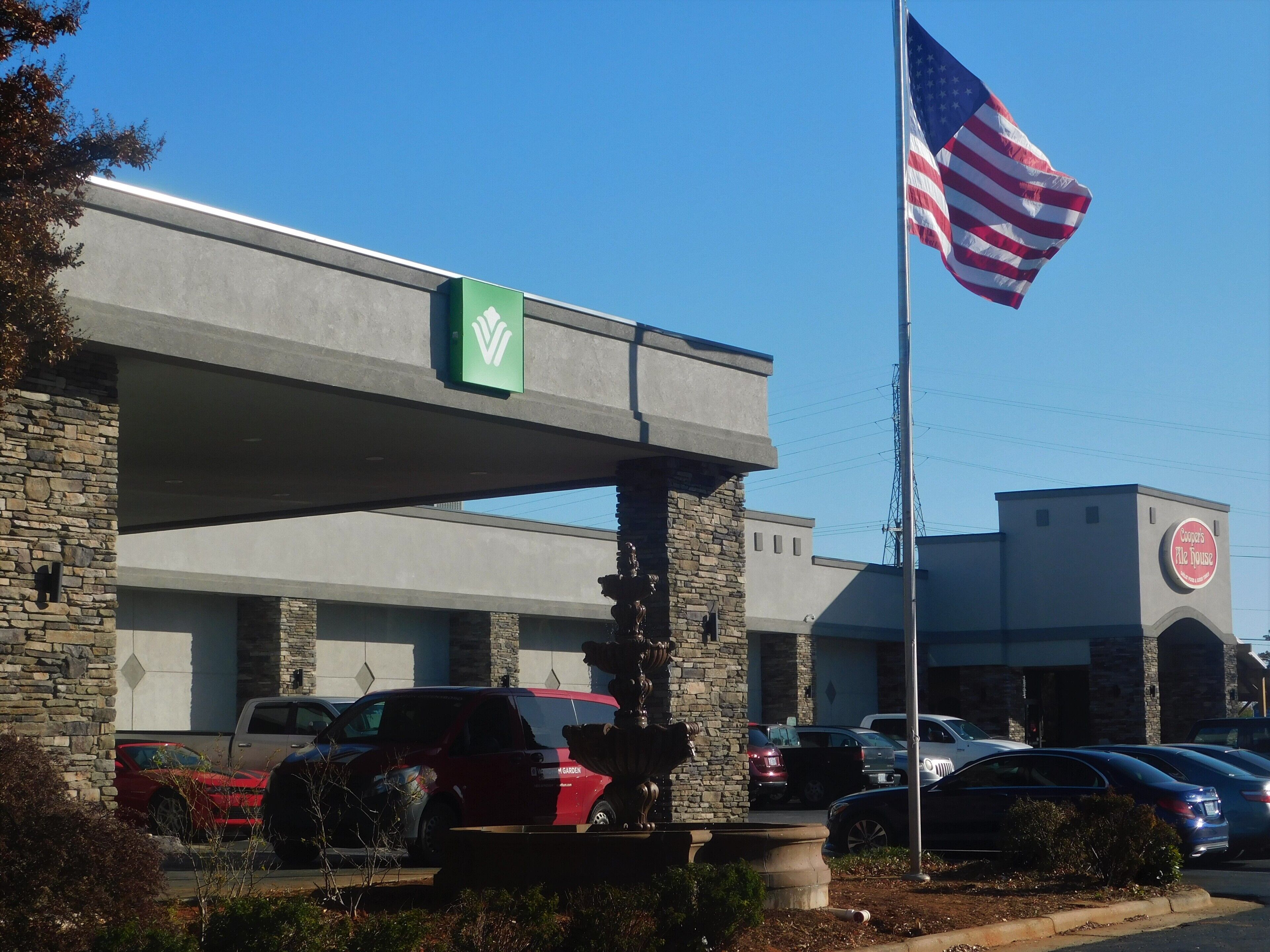 Um edifício com fachada de pedra, um letreiro verde com logotipo branco e uma bandeira americana.