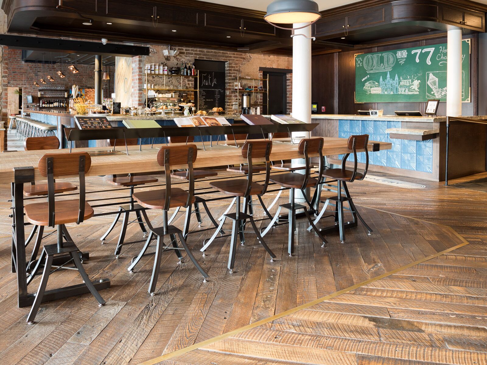 Restaurante com mesas e cadeiras de madeira, um espaço de bar e um cardápio em lousa.