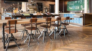 Restaurante com mesas e cadeiras de madeira, um espaço de bar e um cardápio em lousa.