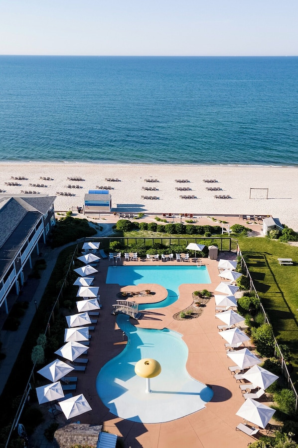 Um resort com área de piscina, cadeiras de praia e vista para o oceano.