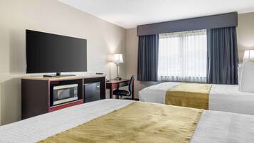 Quarto de hotel com duas camas, uma escrivaninha, televisão, micro-ondas e uma cadeira.