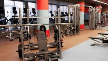Uma academia com diversos equipamentos de exercícios, incluindo esteiras, aparelhos de musculação e pesos livres.