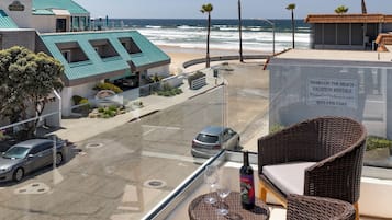 Varanda com móveis de vime com vista para a praia e um estacionamento.
