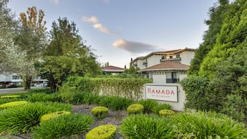 Um jardim bem cuidado com arbustos aparados e uma placa indicando 'Ramada by Wyndham'.