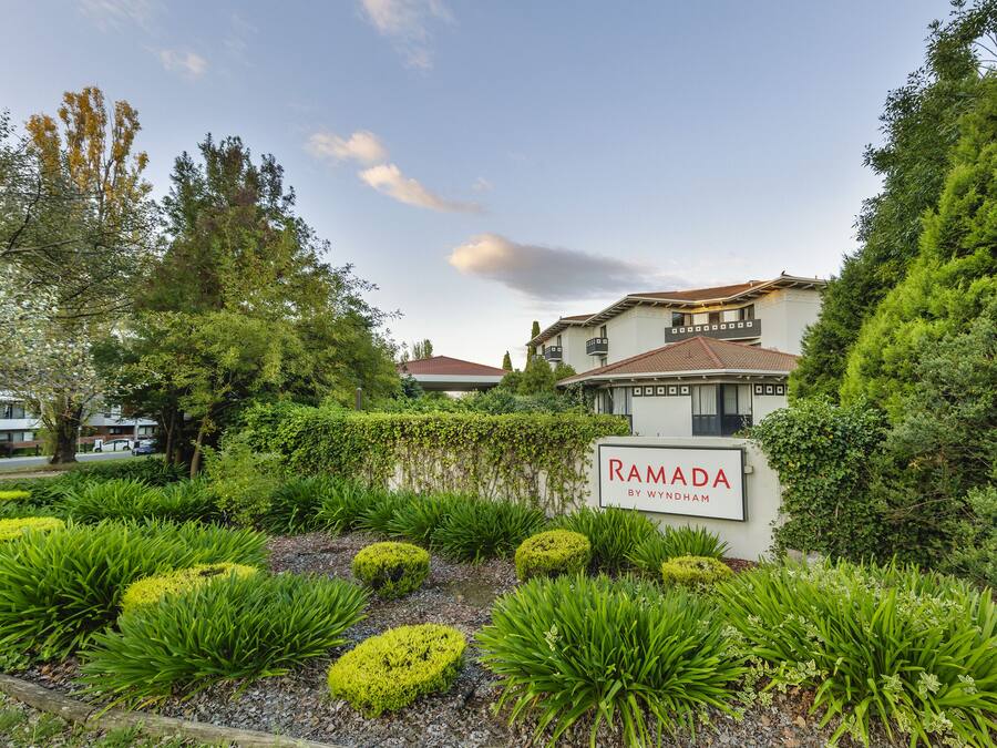 Um jardim bem cuidado com arbustos aparados e uma placa indicando 'Ramada by Wyndham'.