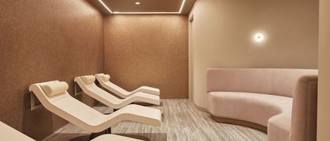 Uma sala de spa moderna com três cadeiras de massagem e um sofá.