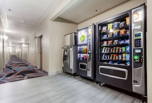 Corredor de hotel com máquinas de venda automática e um pequeno congelador de sorvetes.