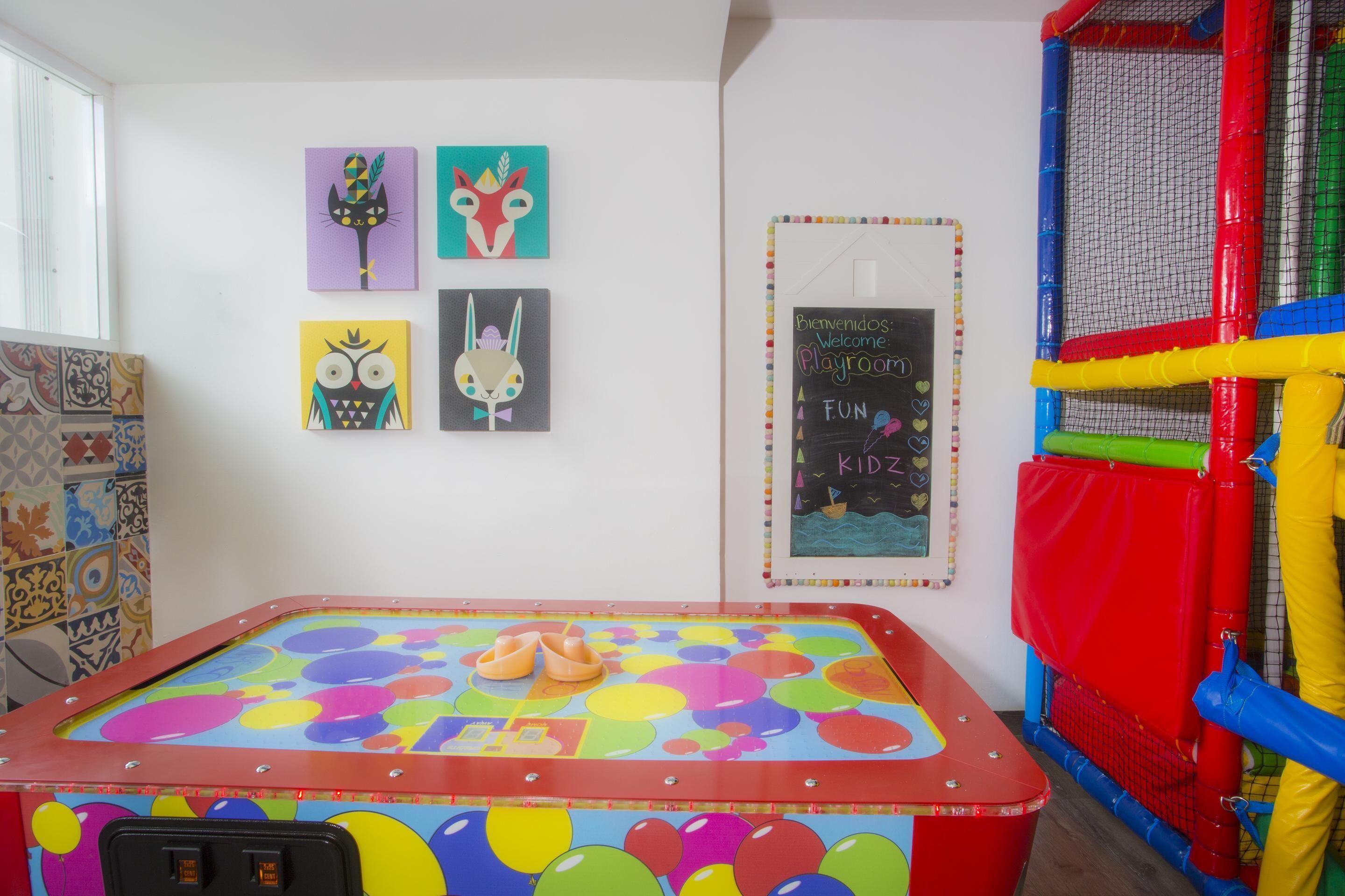 Um espaço de brincadeiras com paredes coloridas, uma mesa de recreação com padrão de bola e uma estrutura de rede para escalar.