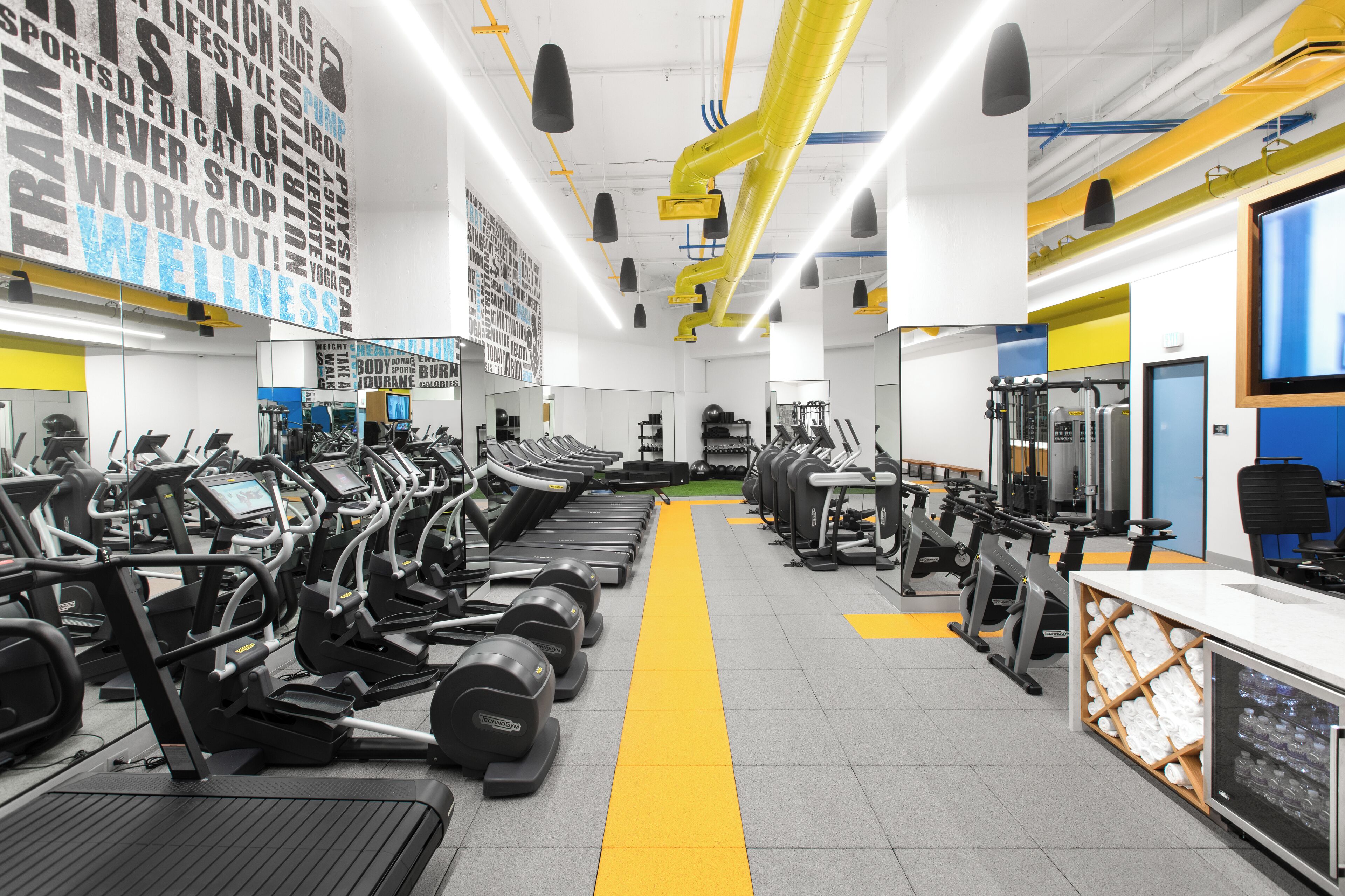 Academia com esteiras, bicicletas ergométricas e aparelhos de musculação.