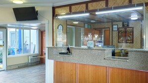 Uma área de recepção com balcão, relógio e porta que dá para o exterior.