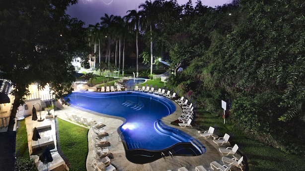 Uma piscina com design único, cercada por espreguiçadeiras e uma área de deck bem iluminada.