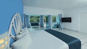 Quarto de hotel com cama, televisão e varanda com cadeira e mesa.