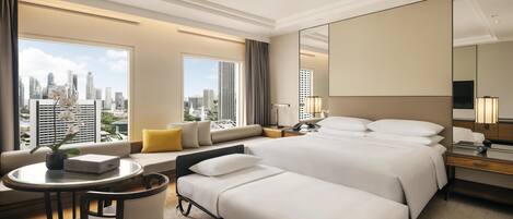 Quarto de hotel com uma cama grande, um sofá, uma mesa de jantar e vista para a cidade.