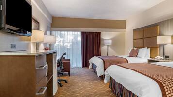 Quarto de hotel com duas camas, televisão, escrivaninha e cadeira.