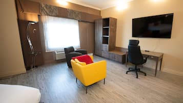 Quarto moderno com poltrona amarela, cadeira de escritório preta, televisão de tela plana e uma janela grande com cortinas.