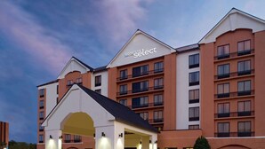 Um hotel com vários andares, entrada destacada, varandas e céu claro.