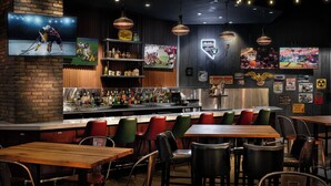 Uma área de bar com diversas opções de assento, variedade de garrafas nas prateleiras e objetos de colecionador esportivo nas paredes.