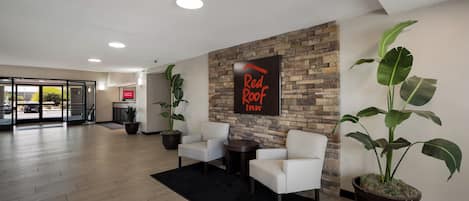 Um saguão de hotel com balcão de recepção, área de estar e placa da Red Roof Inn.