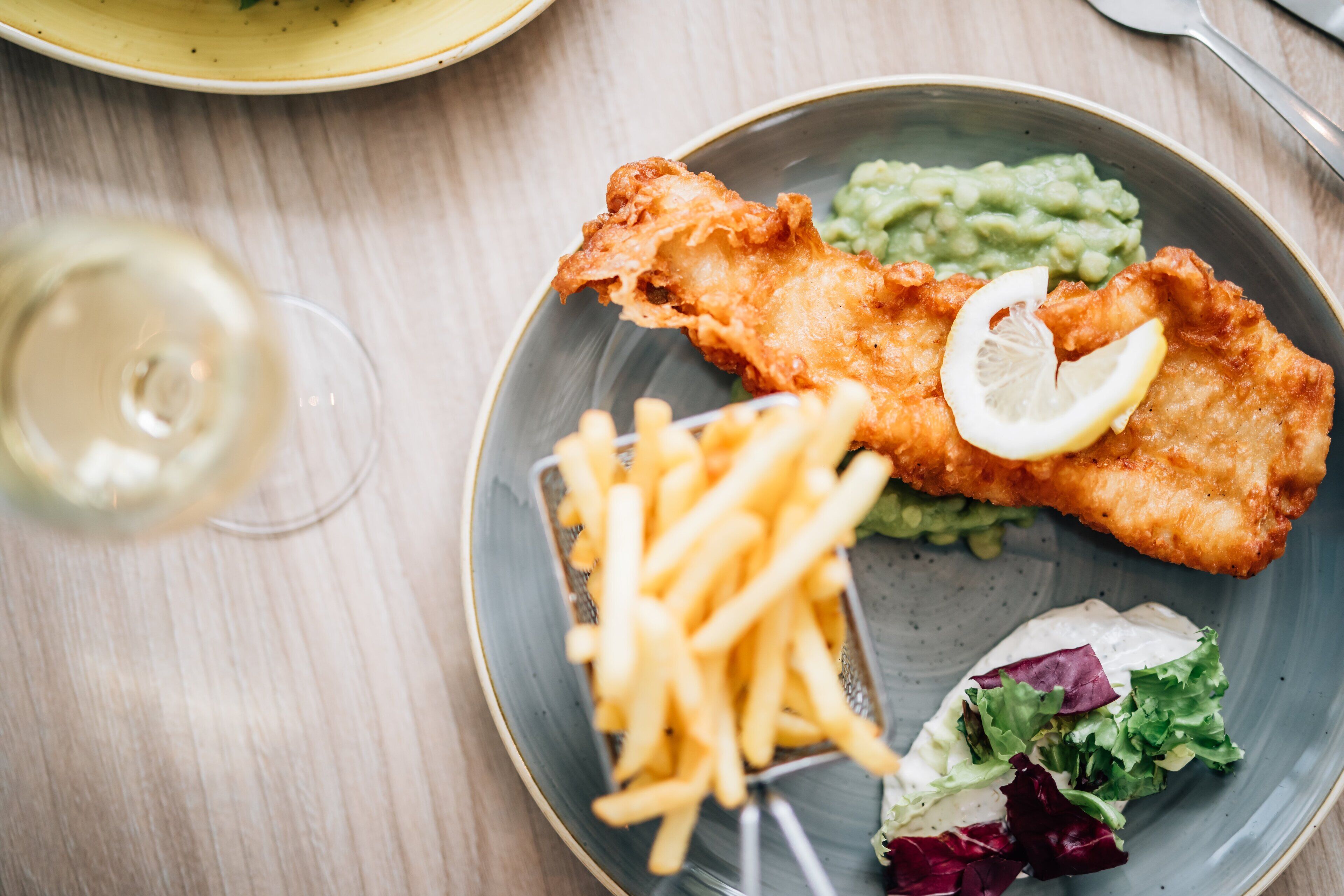 Um prato com um filé de peixe empanado, batatas fritas e uma salada.