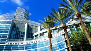 Centro de Convenções Anaheim com fachada de vidro moderna e palmeiras em primeiro plano.
