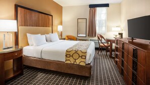 Quarto de hotel com uma cama grande, uma escrivaninha, uma cadeira, uma televisão e um guarda-roupa.