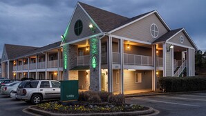 Um motel com vários andares, pátio central, varandas e estacionamento.