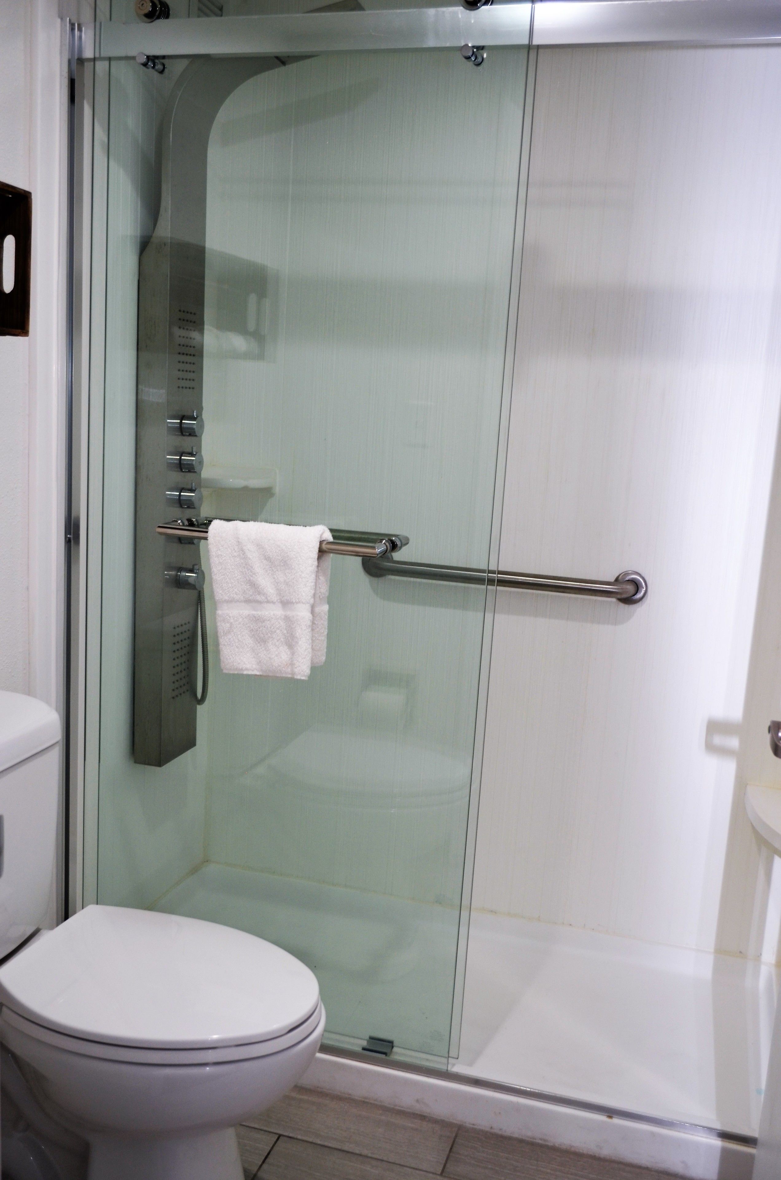 Box de chuveiro com paredes de vidro, um porta-toalhas e um vaso sanitário.