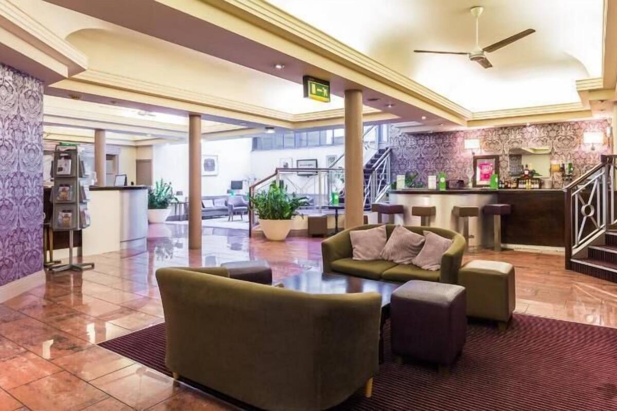 Um hall amplo com balcão de recepção, área de estar, escada e bar.