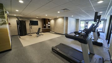 Academia com esteiras, bicicleta ergométrica e aparelho de musculação.