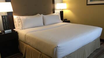 Quarto de hotel com uma cama grande, duas mesas de cabeceira, um painel de cabeceira e duas luminárias fixadas na parede.